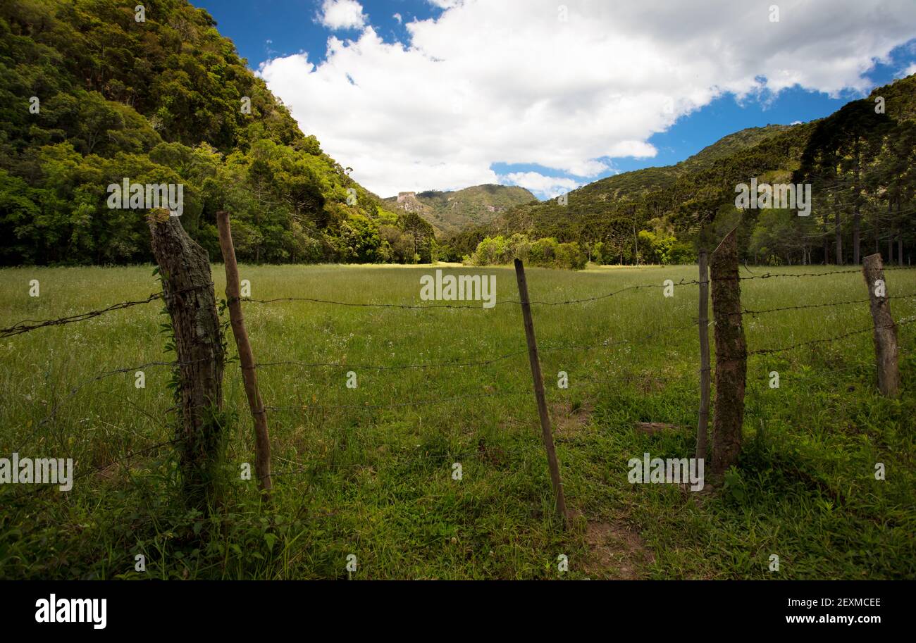 A greenfield with mountains background behind barbed wire in Southern ...