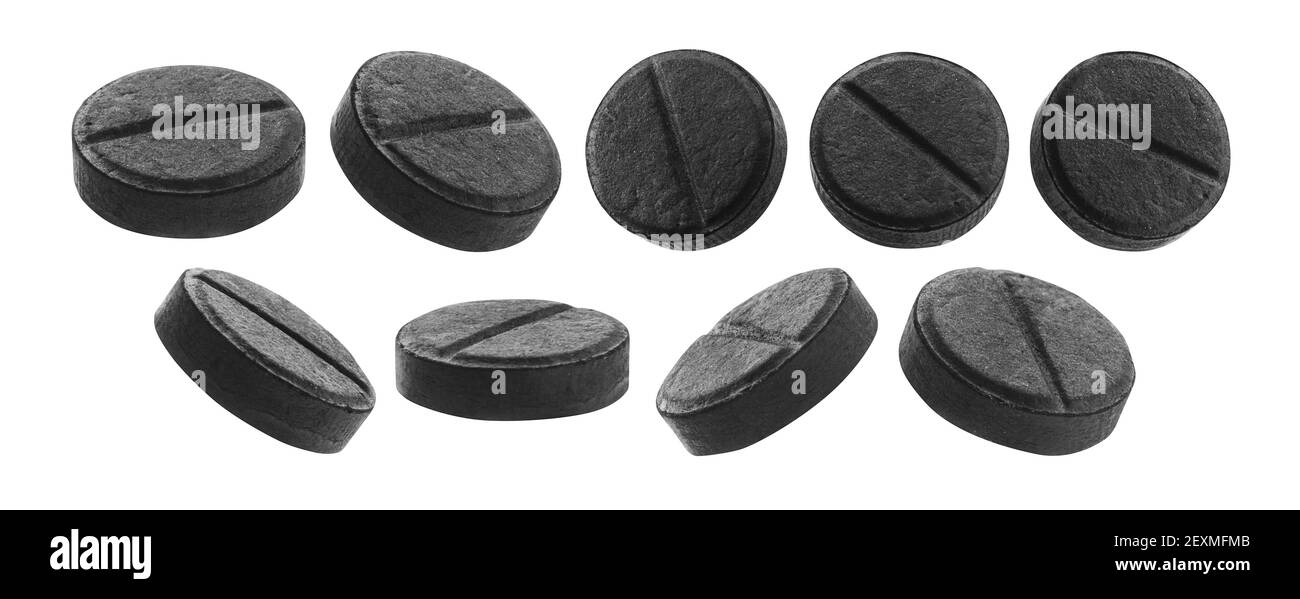 A set of black activated carbon tablets. Isolated on a white background ...