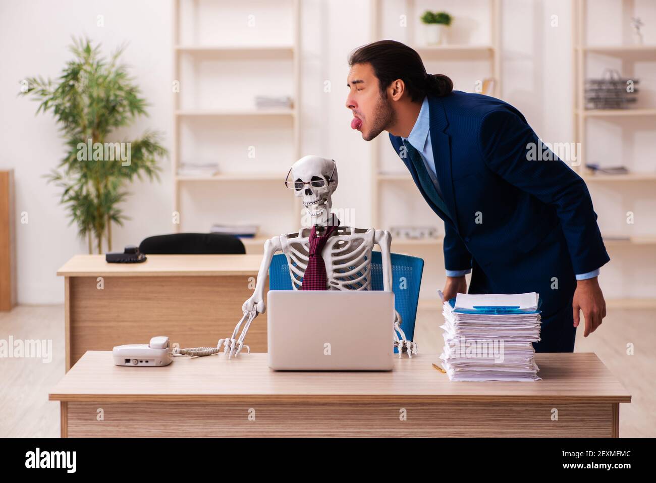 Dead employee working in the office in funny concept Stock Photo - Alamy