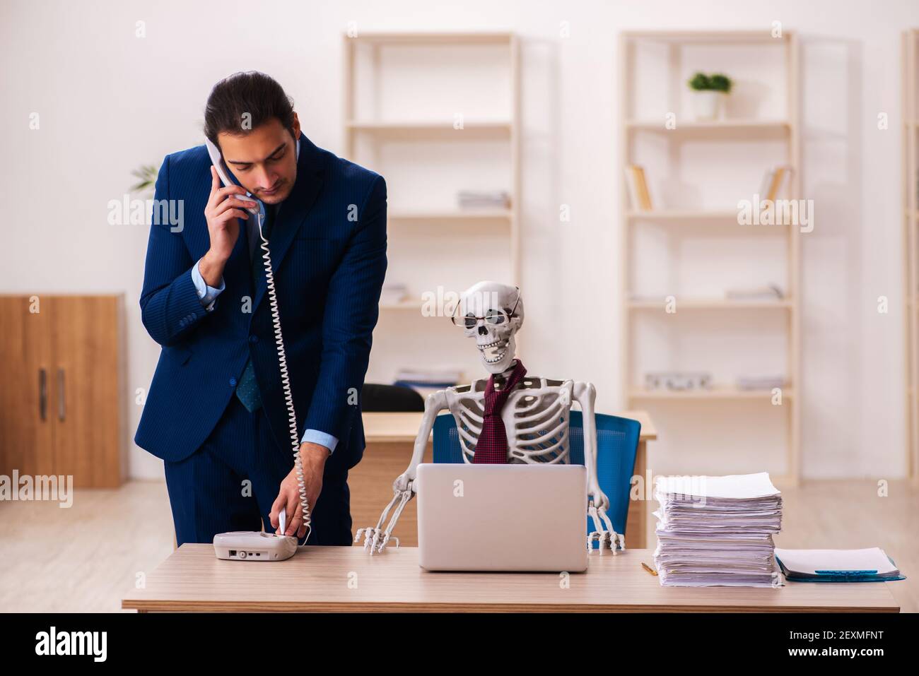 Dead employee working in the office in funny concept Stock Photo - Alamy