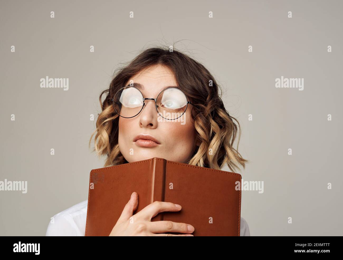 Woman with glasses holds a book in her hand on a gray background short ...