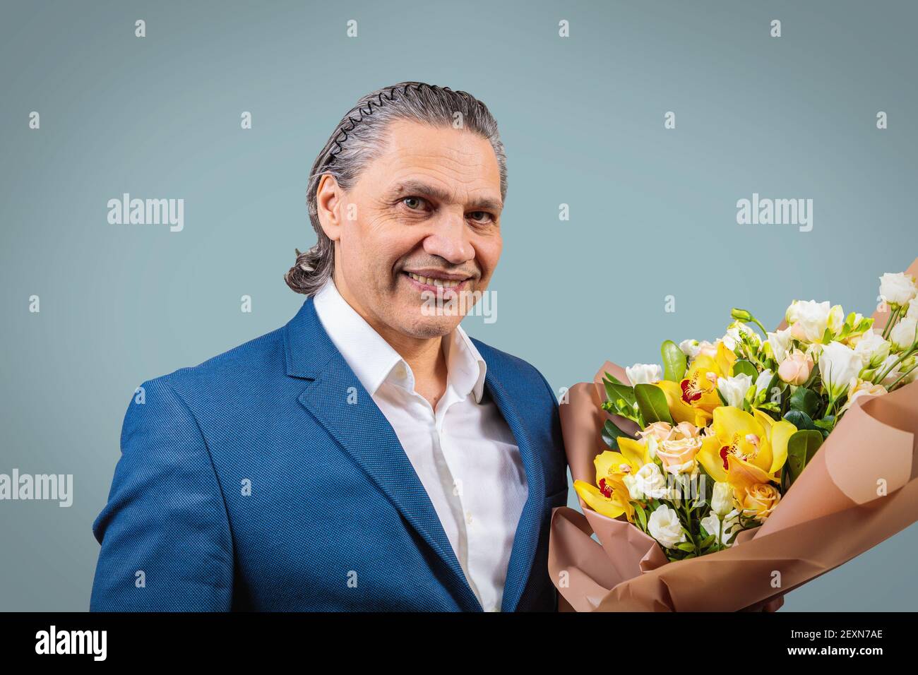 Smiling 50-year-old man in a blue jacket with a bouquet of flowers on a ...