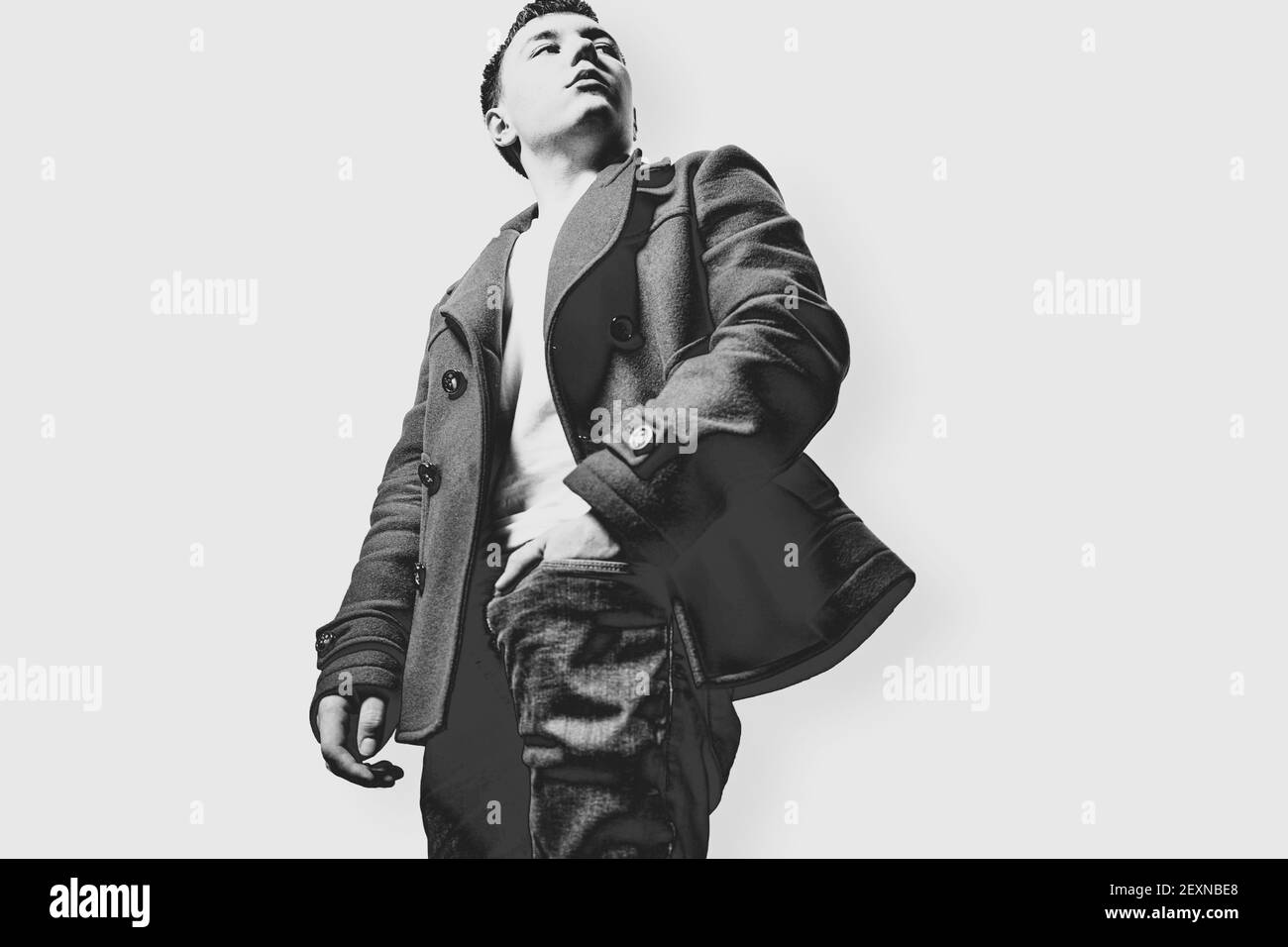A low angle grayscale shot of a handsome male on the white background ...