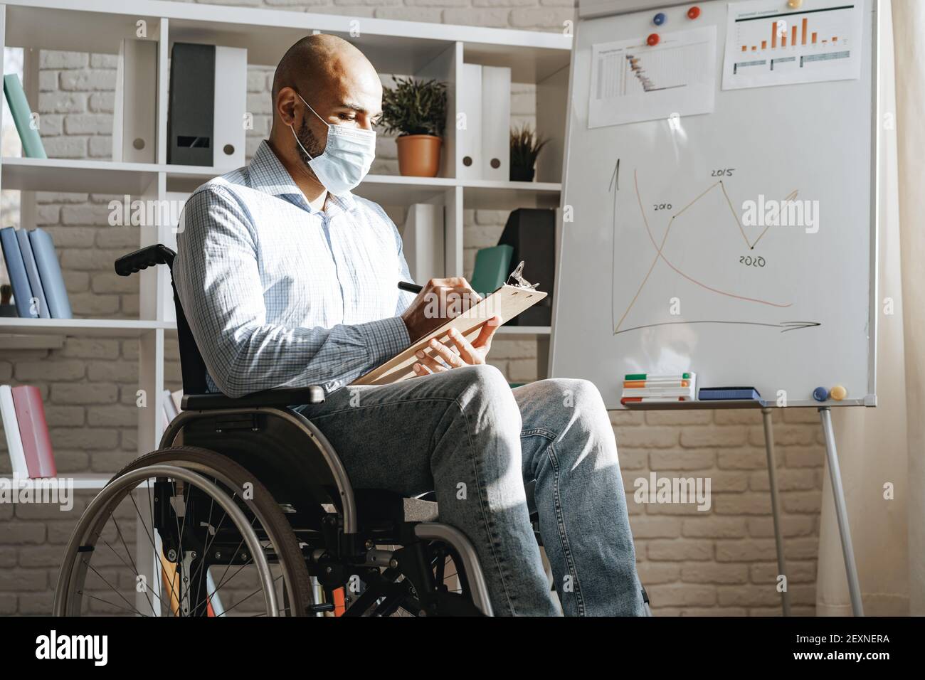 Disabled young man making presentation in office wearing medical mask ...