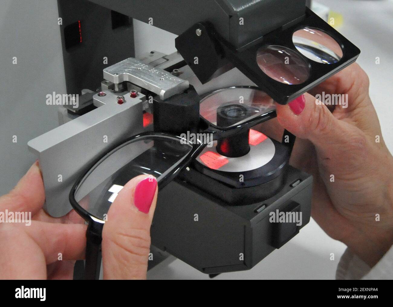 Lab tech Alice Boughan checks the prescription for new eyeglass lenses ...