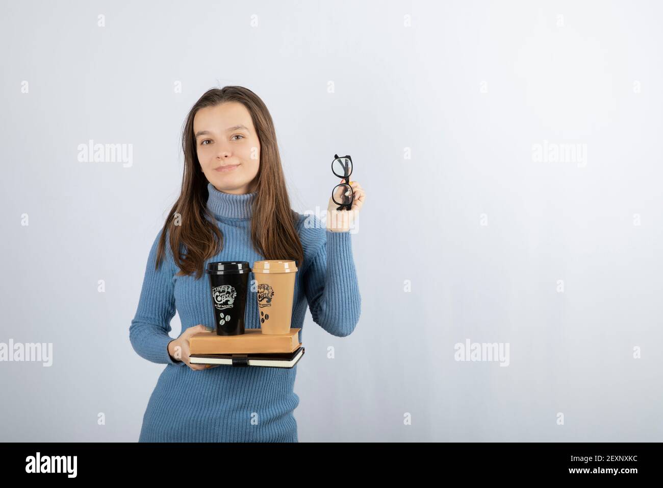 Image of a young girl model holding books and two cups of coffee Stock ...