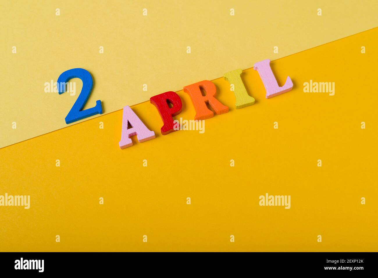 Wooden letters the second of April on a yellow background ...