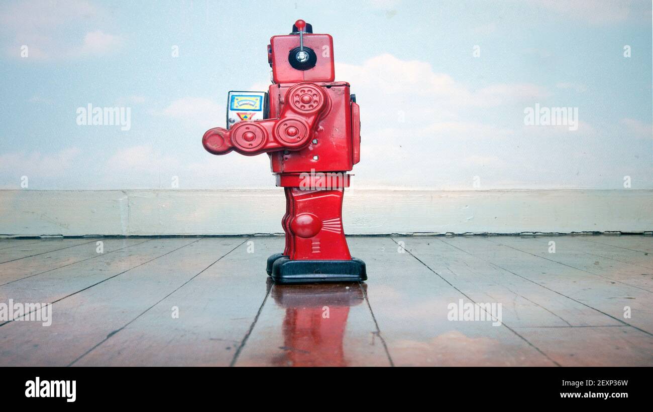retro robot toy on a old wooden floor with sky and clouds background ...
