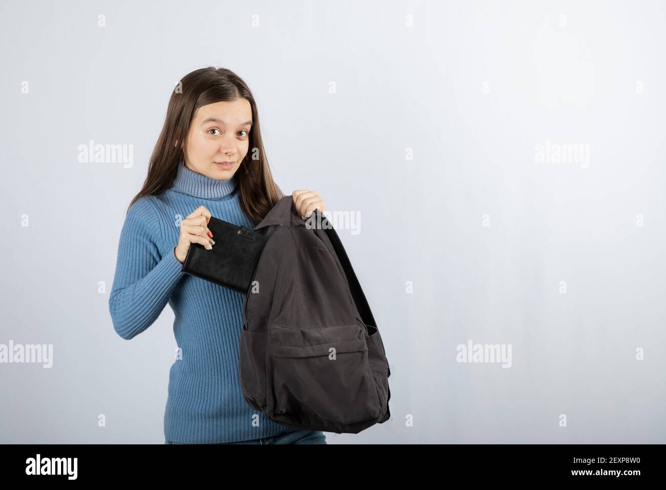Image of a young girl student putting notebook in backpack Stock Photo ...