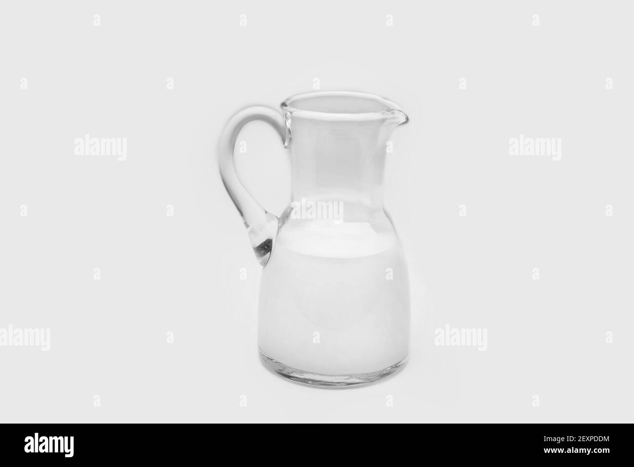 Glass pitcher half full with milk on a white background Stock Photo - Alamy