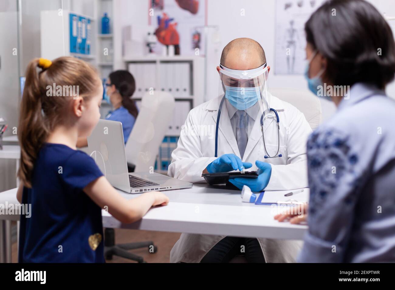 Pediatrician doctor writing notes on notepad during medical checkup ...