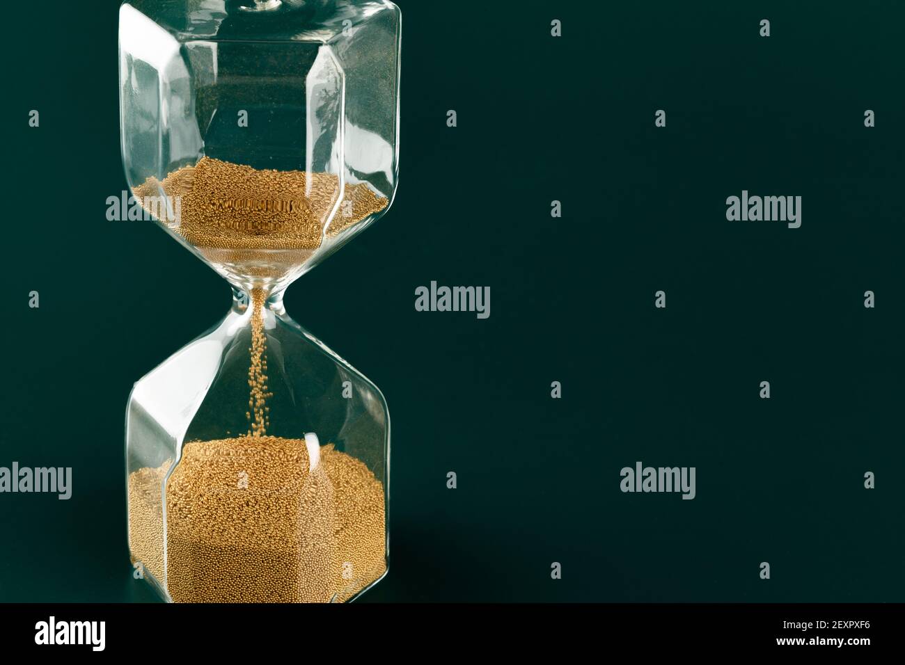 Gold hourglass on dark green paper background Stock Photo - Alamy