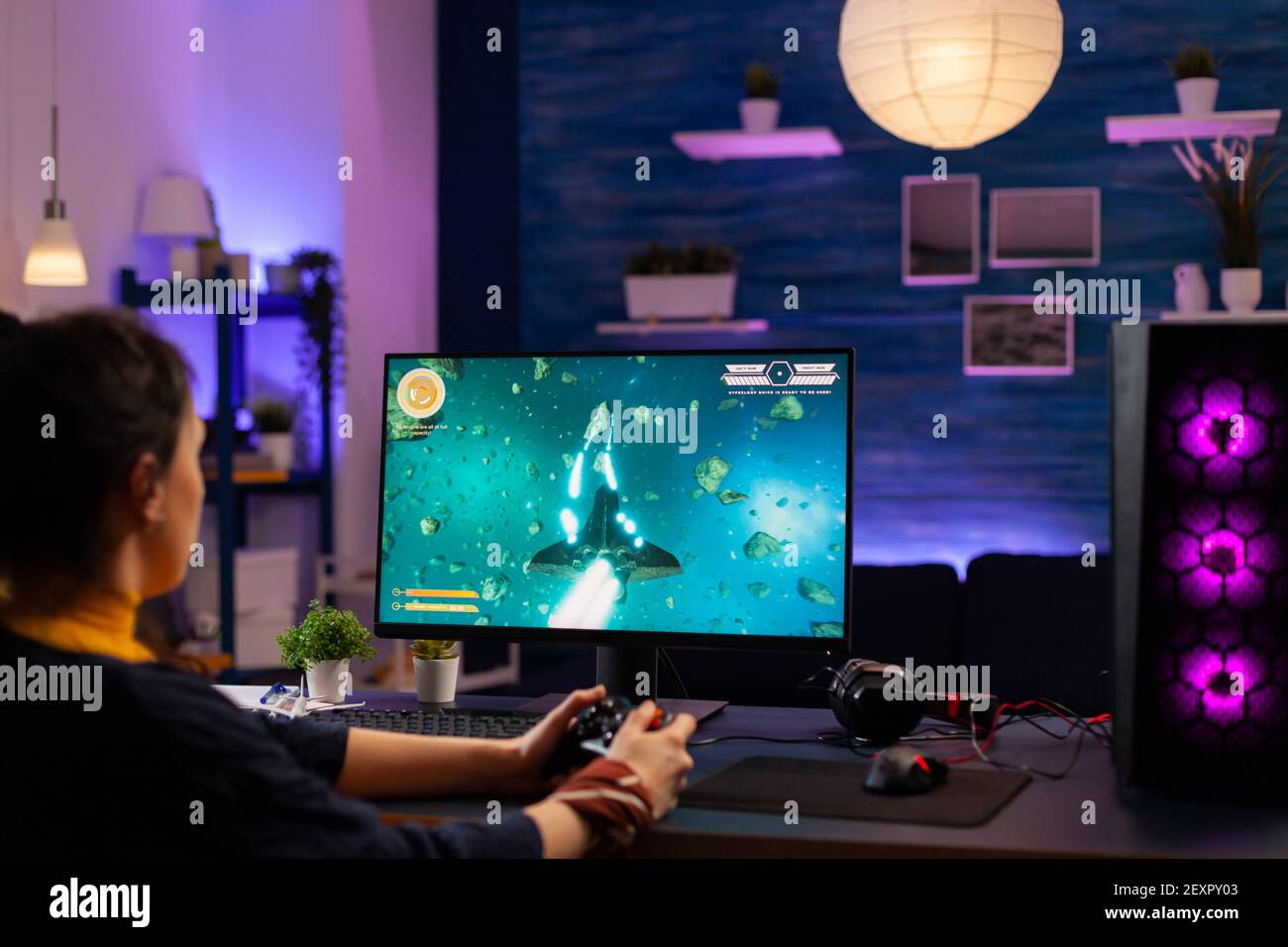 Concentrated player sitting on gaming desk late at night using wireless ...