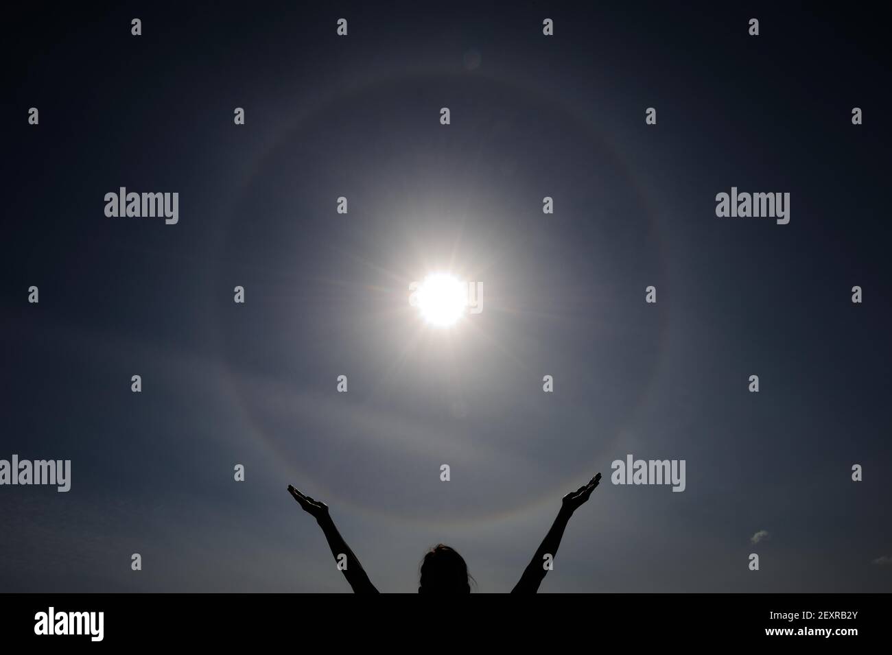 Kimberley Daglen appears to hold up the solar halo viewed over North ...