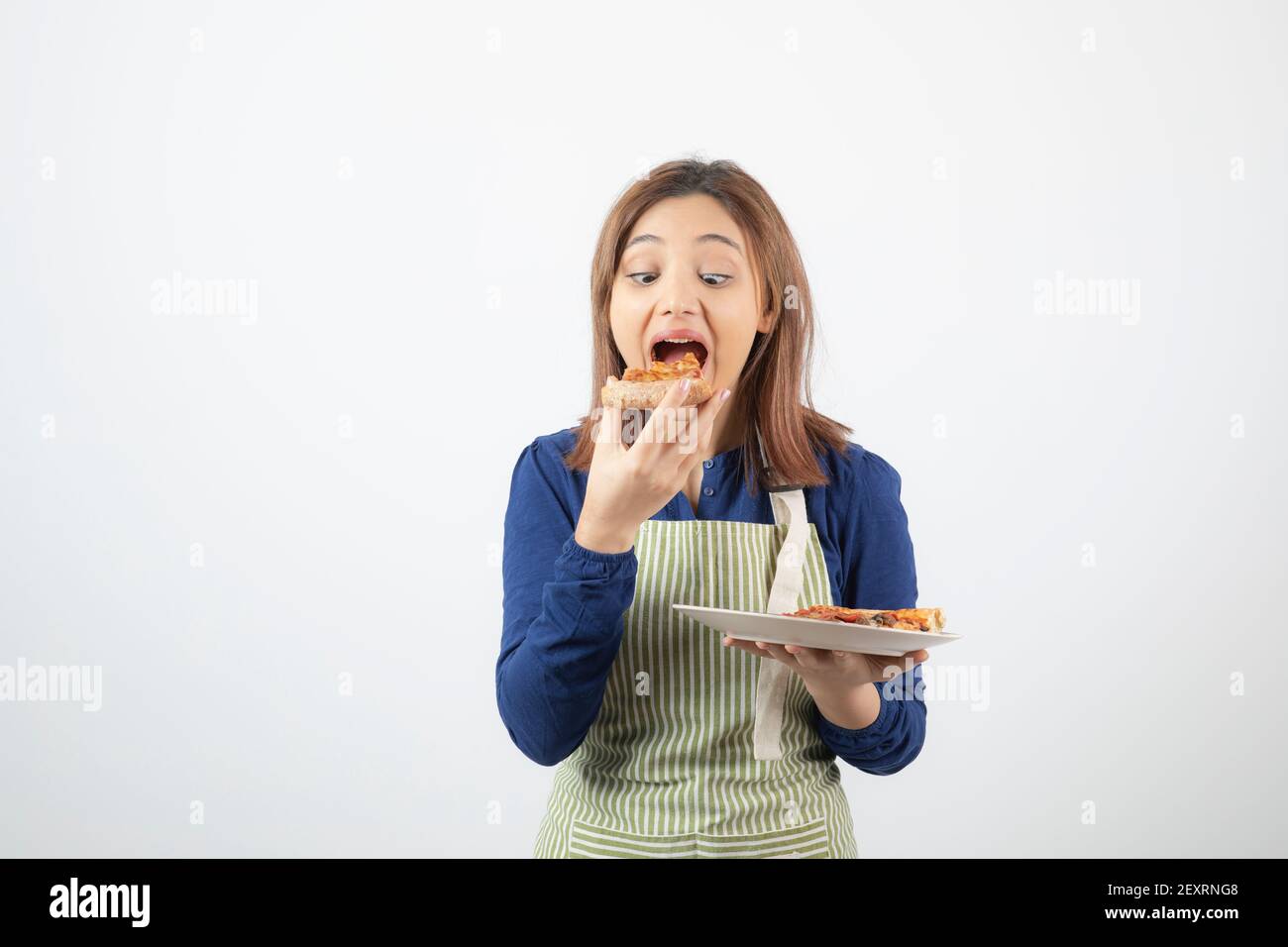 Photo of a cute young woman model in apron eating pizza Stock Photo - Alamy
