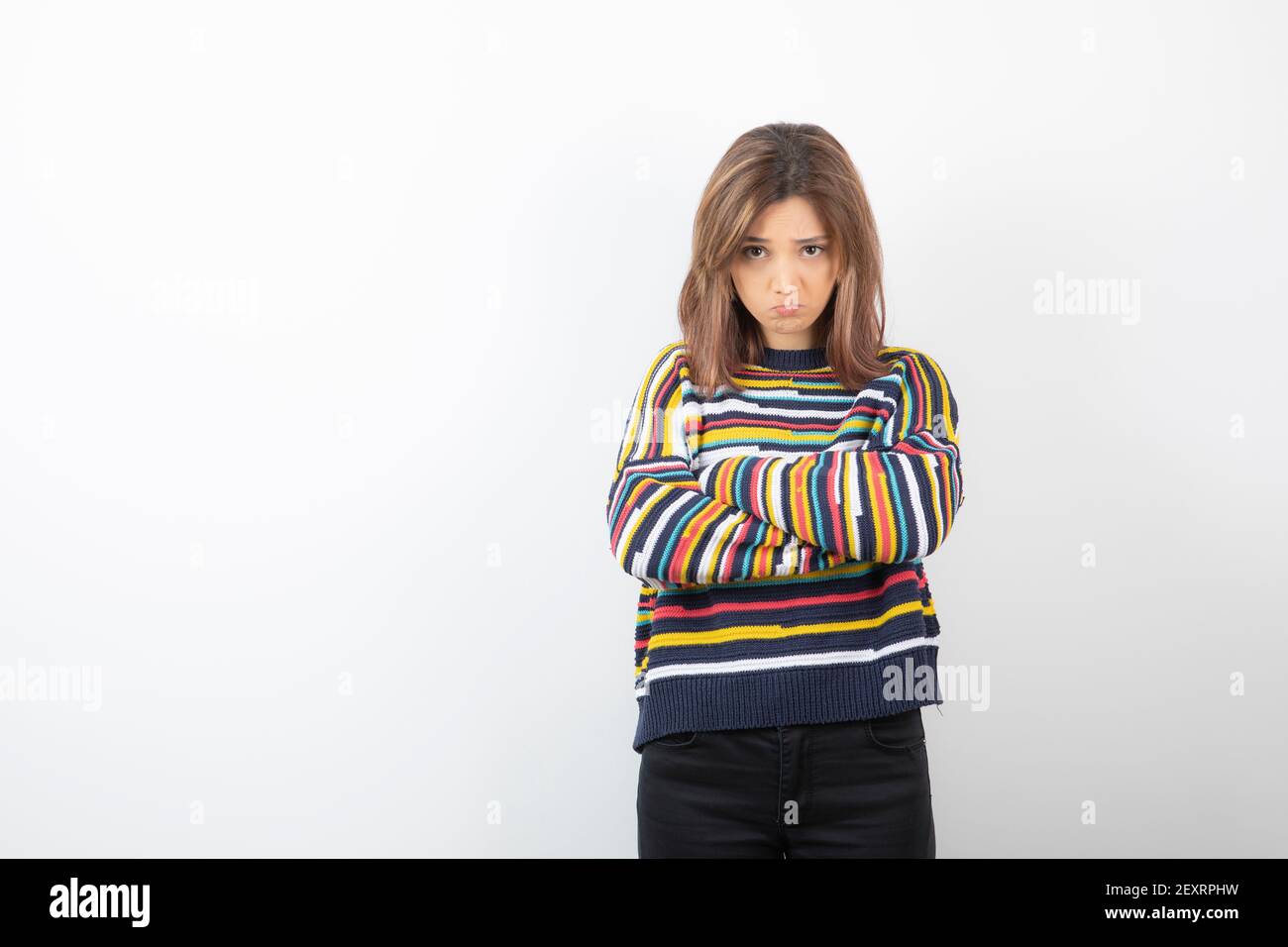Photo of a cute young woman model standing and posing with crossed arms ...