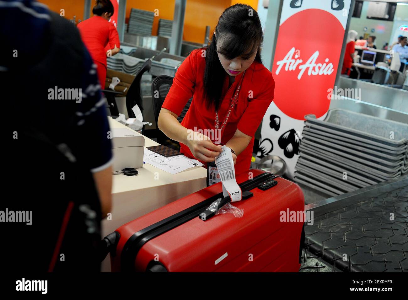 An AirAsia ground crew secures passenger's luggage check-in sticker at ...
