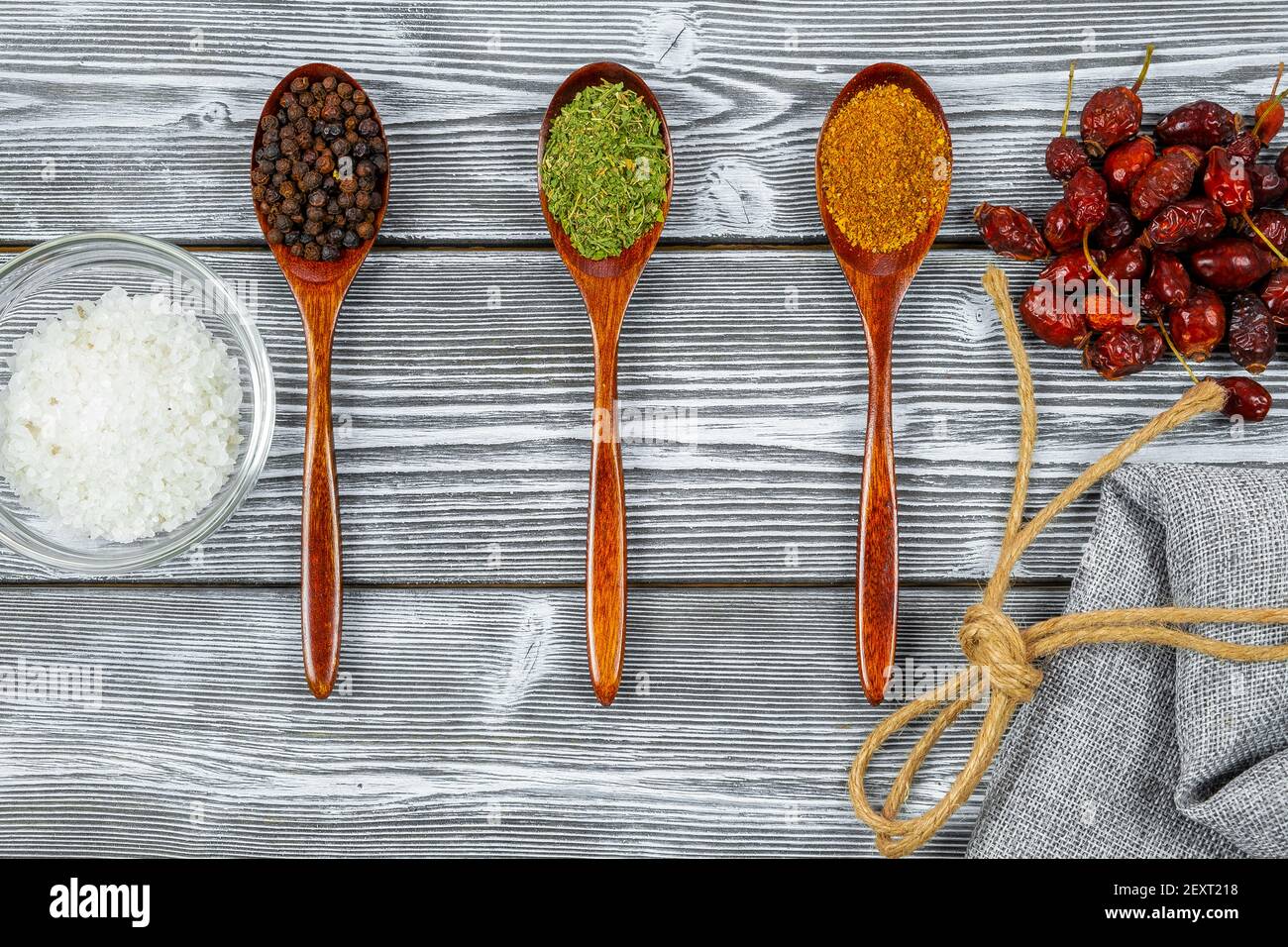 Spoons of various spices on a rustic wooden table. Top view. The ...