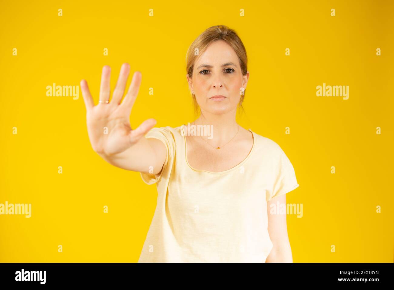 Young woman making stop sign with hand, saying no, looking at camera ...