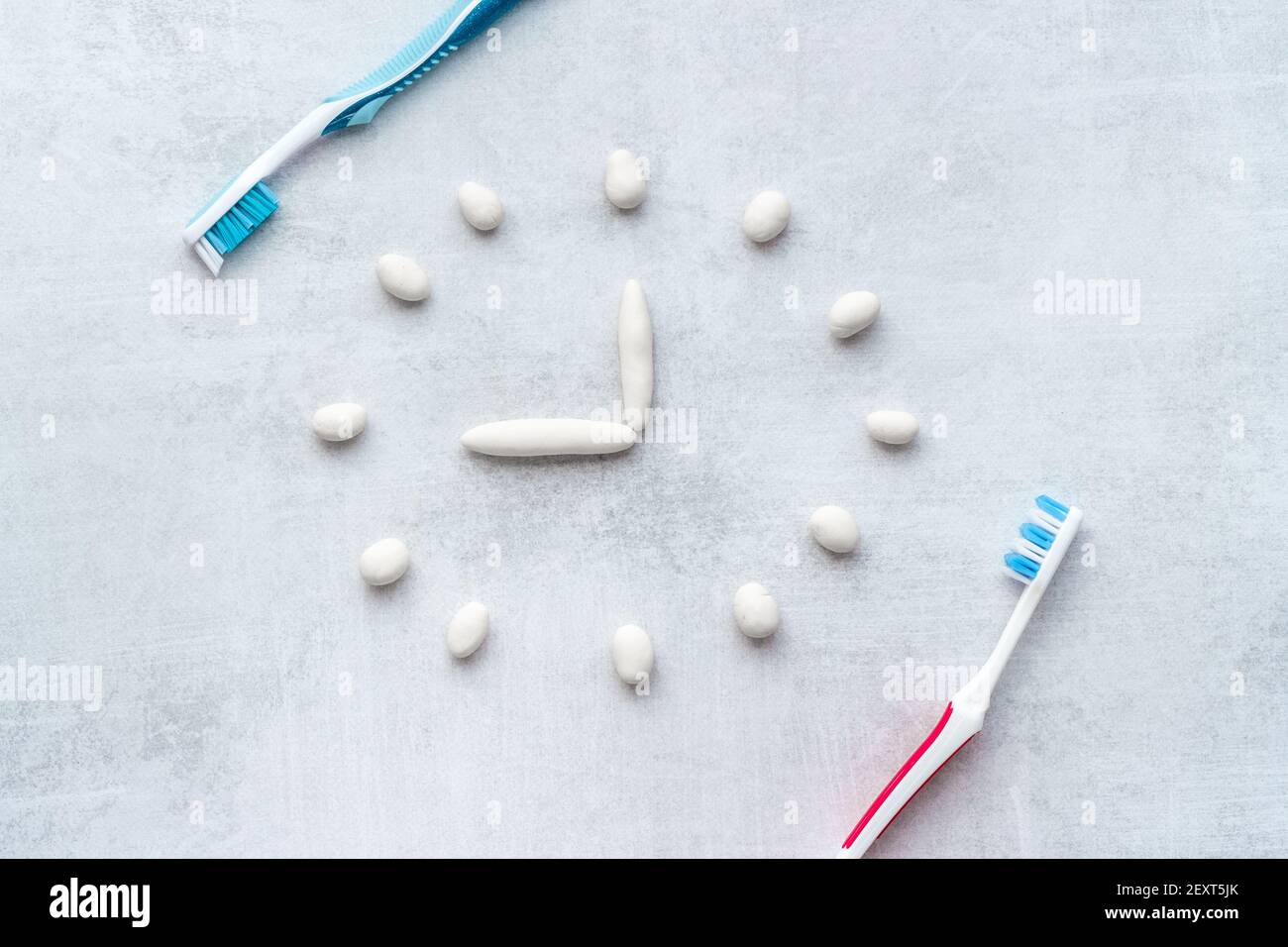 Morning routine concept. Clock made of toothpaste with toothbrushes ...