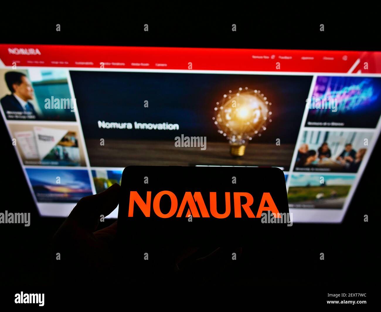 Person holding mobile phone with logo of Japanese financial company ...