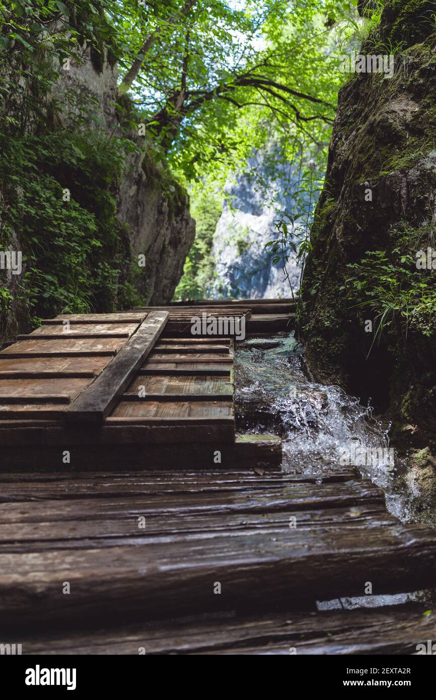A closeup of a wooden stairway on the water streaming from the rocks in ...