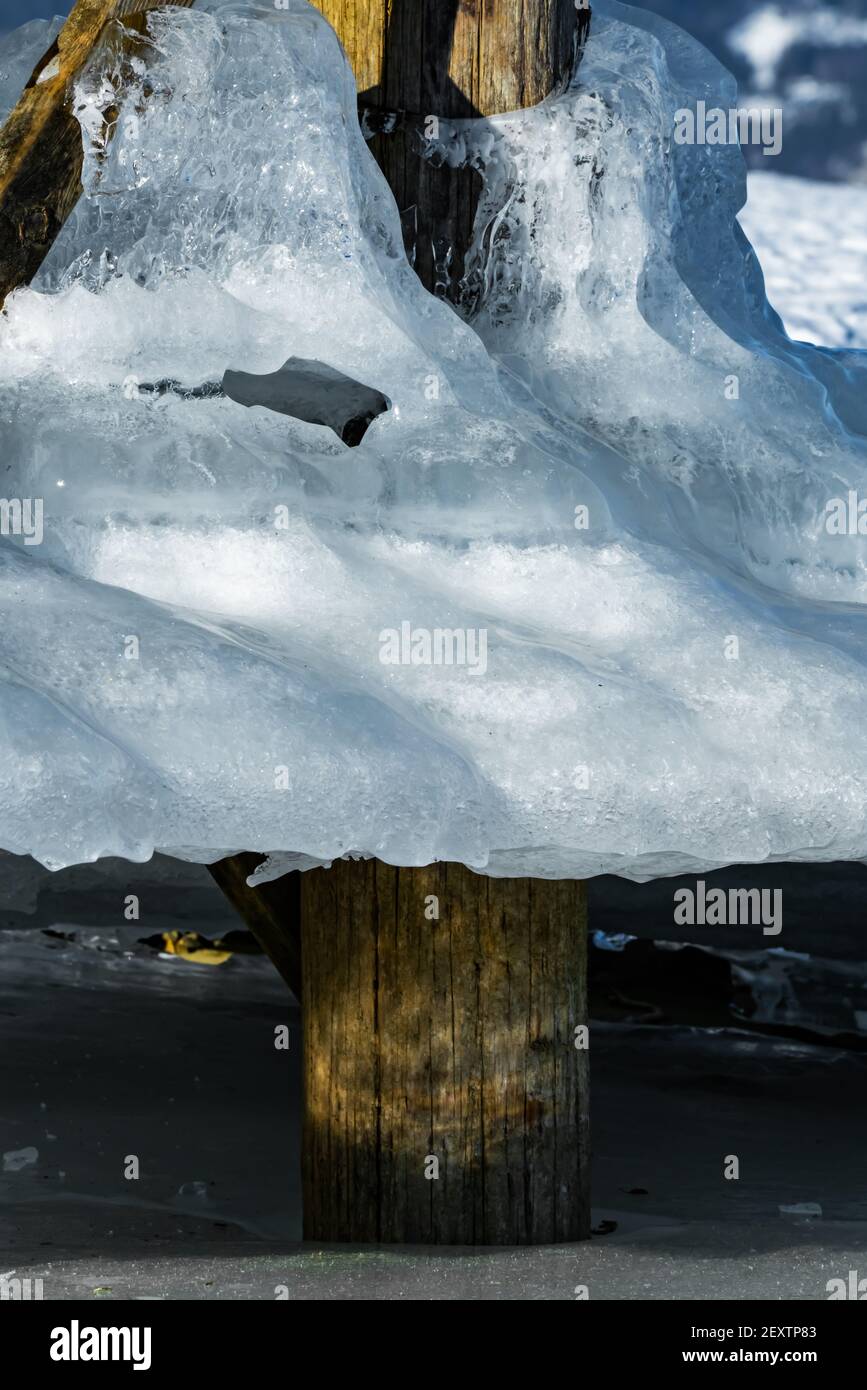 Thick sea ice on the wooden pillar of an old pier. Close up Stock Photo ...