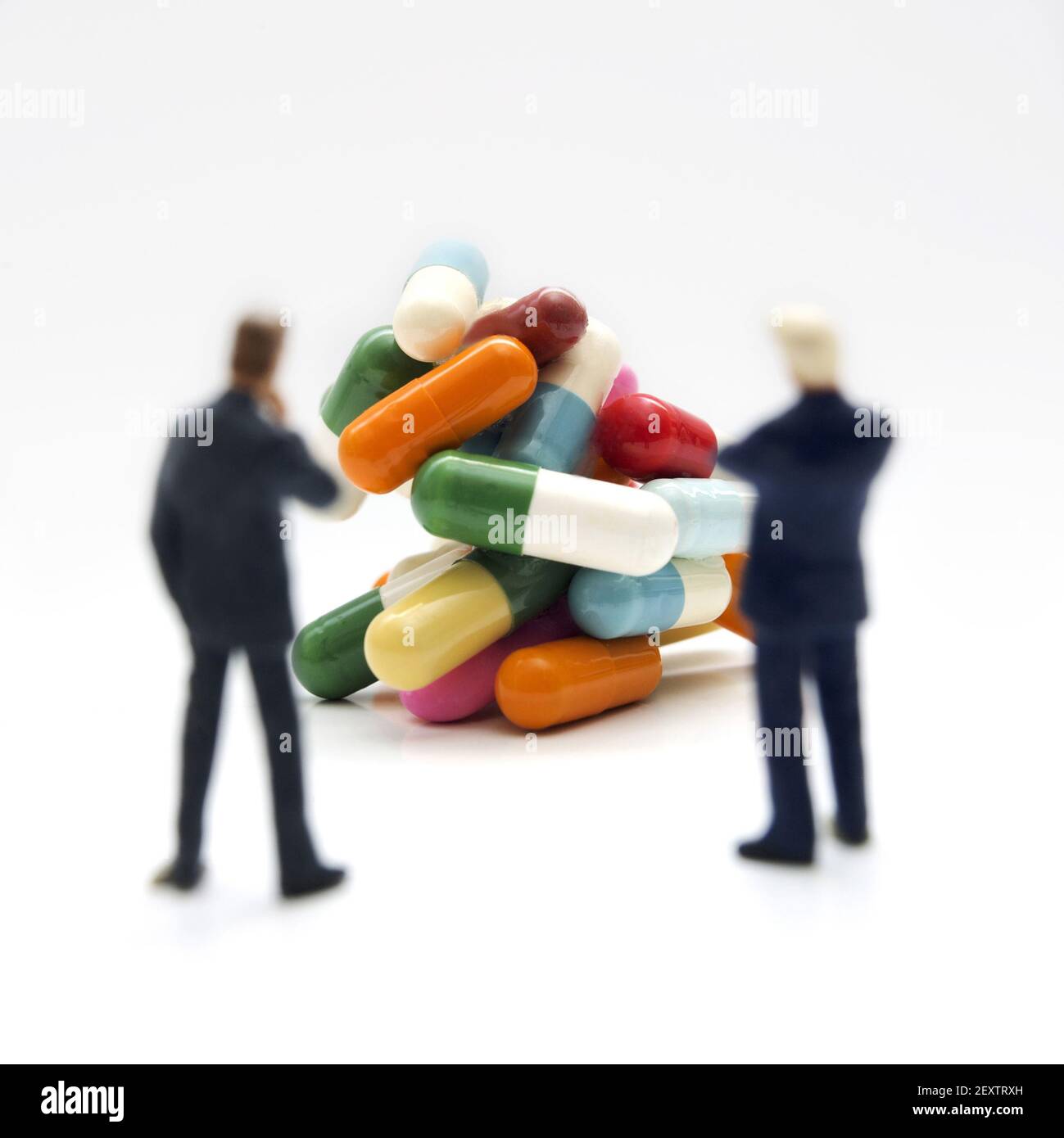 A closeup of two male figures observing a pile of capsules on the white ...