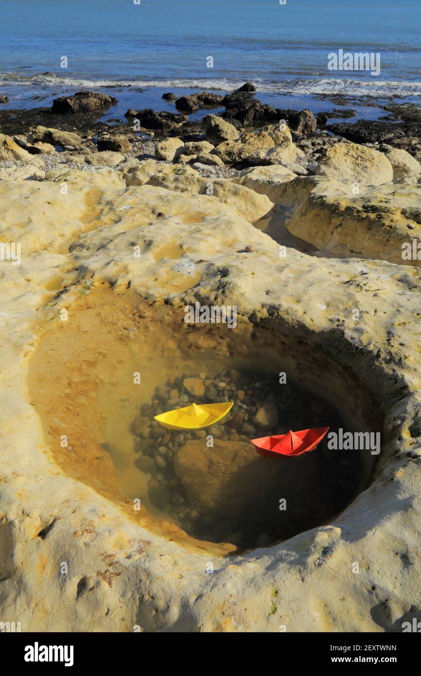 Paper boats in puddle on the rocky beach near village of Beer in Devon ...