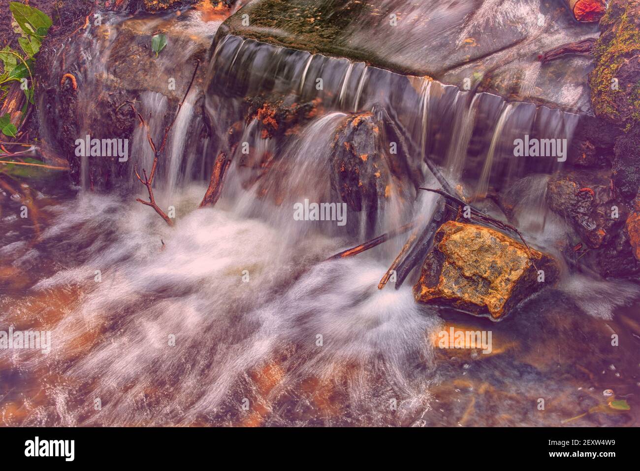 Intimate landscape of stream rushing over a waterfall in a woodland ...