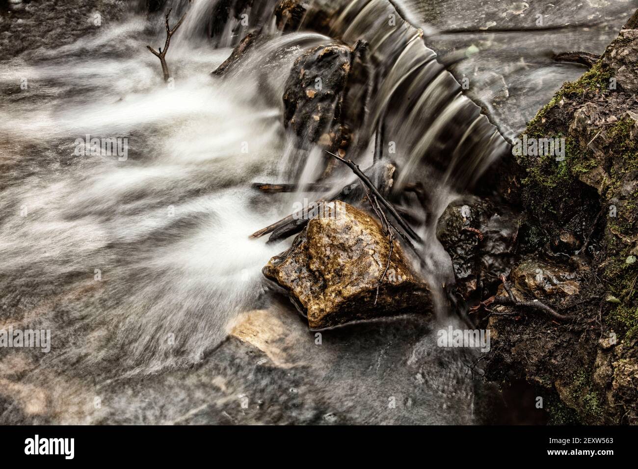Intimate landscape of stream rushing over a waterfall in a woodland ...