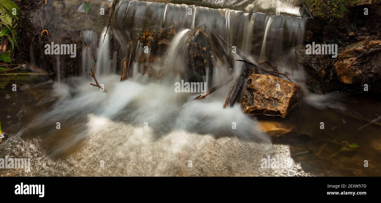 Intimate landscape of stream rushing over a waterfall in a woodland ...