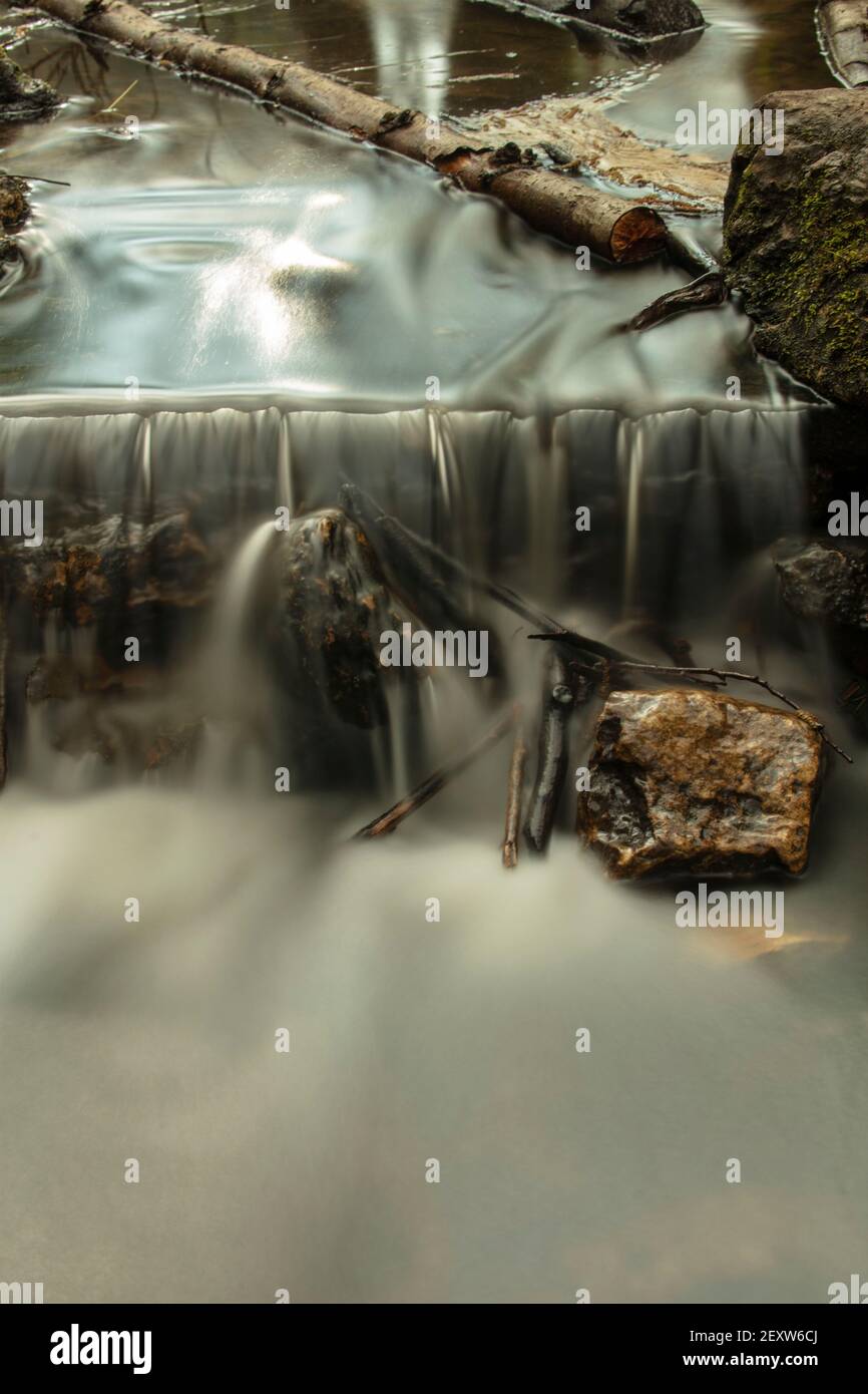 Intimate landscape of stream rushing over a waterfall in a woodland ...
