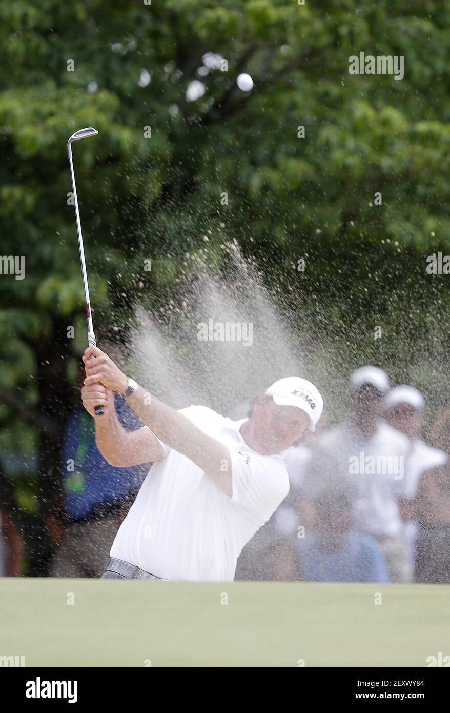 Phil Mickelson is obscured by sand from the bunker next to the 12th ...