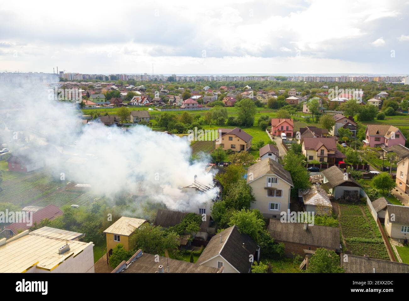 Aerial view of a house on fire with orange flames and white thick smoke ...