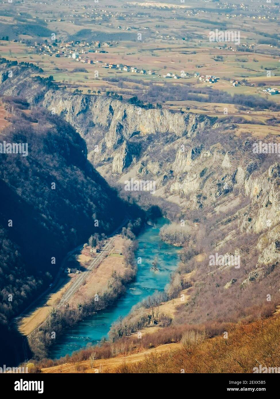 A vertical shot of a blue-water river surrounded by canyons in a rural ...