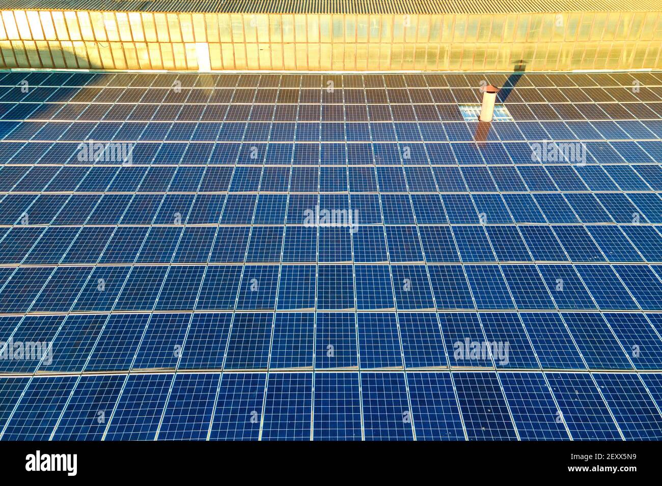 Blue photovoltaic solar panels mounted on industrial building roof for ...