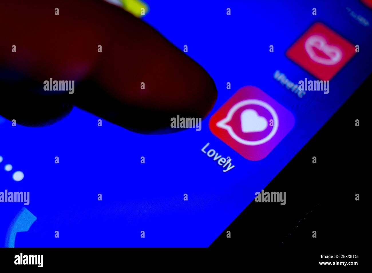 Madrid, Spain- March 3, 2021: Finger pressing Lovely app icon next to ...