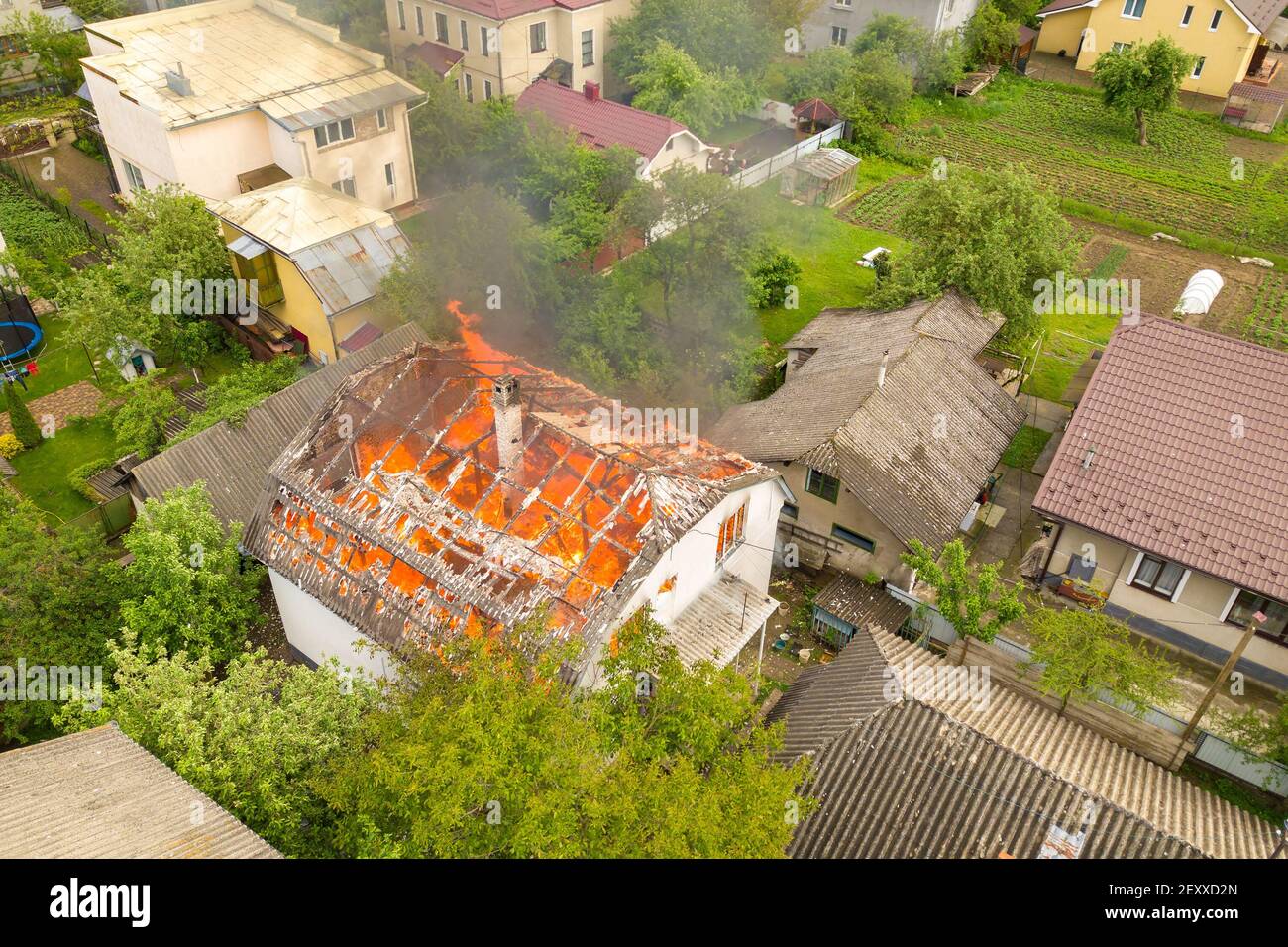 Aerial view of a house on fire with orange flames and white thick smoke ...