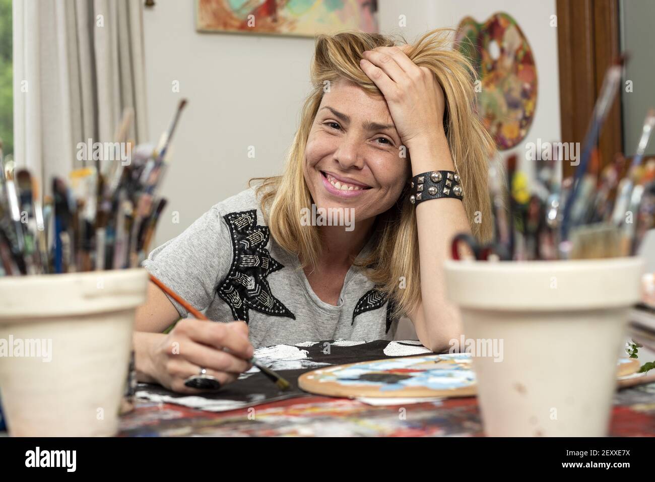 A closeup shot of a smiling female artist painting in the art studio - authentic concept Stock ...