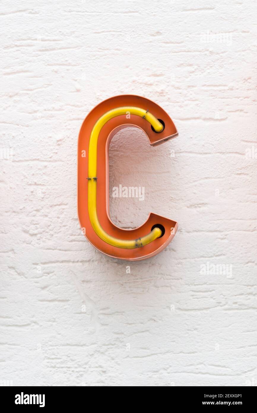 Yellow neon letter c mounted on orange-coloured metal letter Stock ...