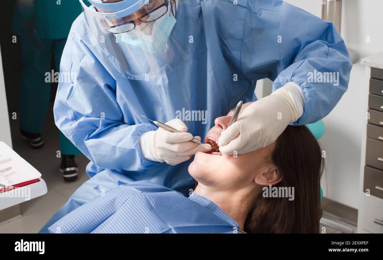 dentist working with personal protective equipment, female patient, in ...