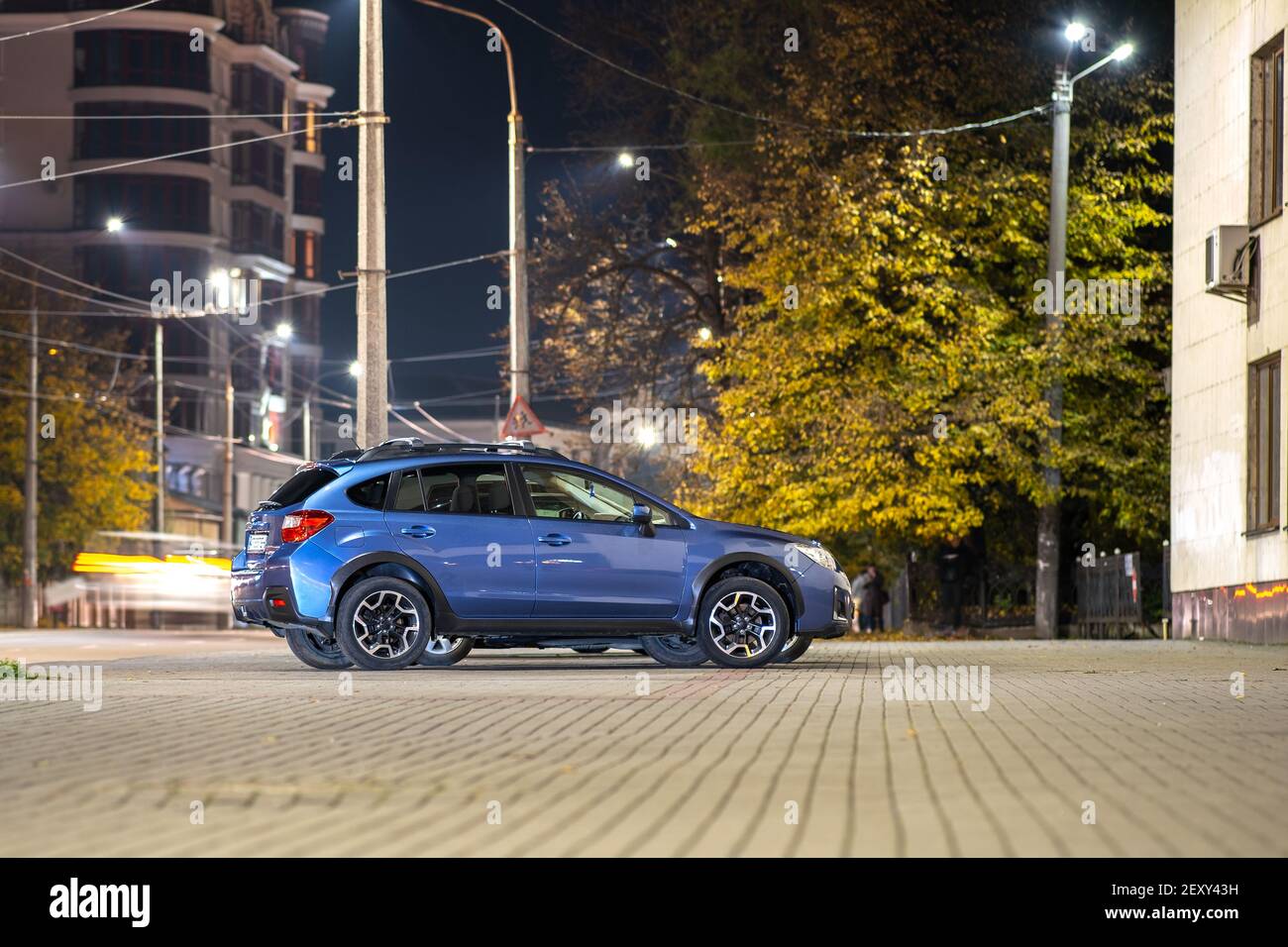 Blue car parked on brightly illuminated city street at night Stock ...