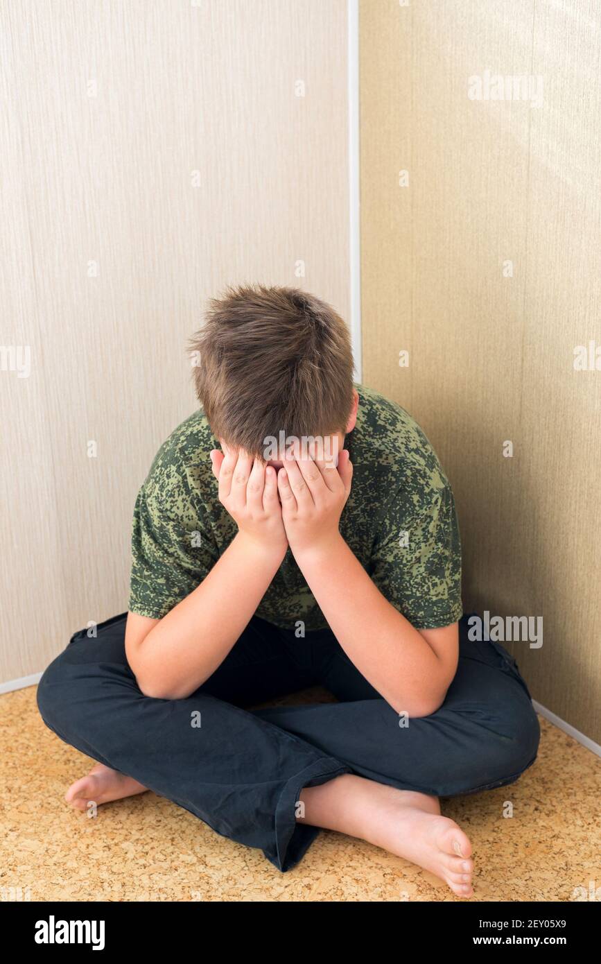 Boy teenager with depression sitting in the corner of room Stock Photo ...
