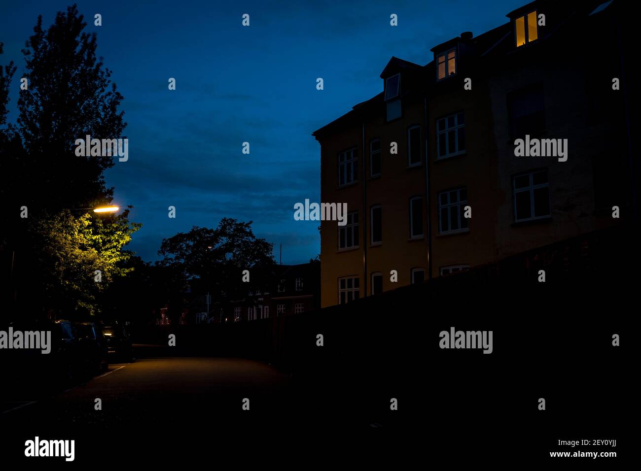 A tall yellow building at night with the lights off Stock Photo - Alamy