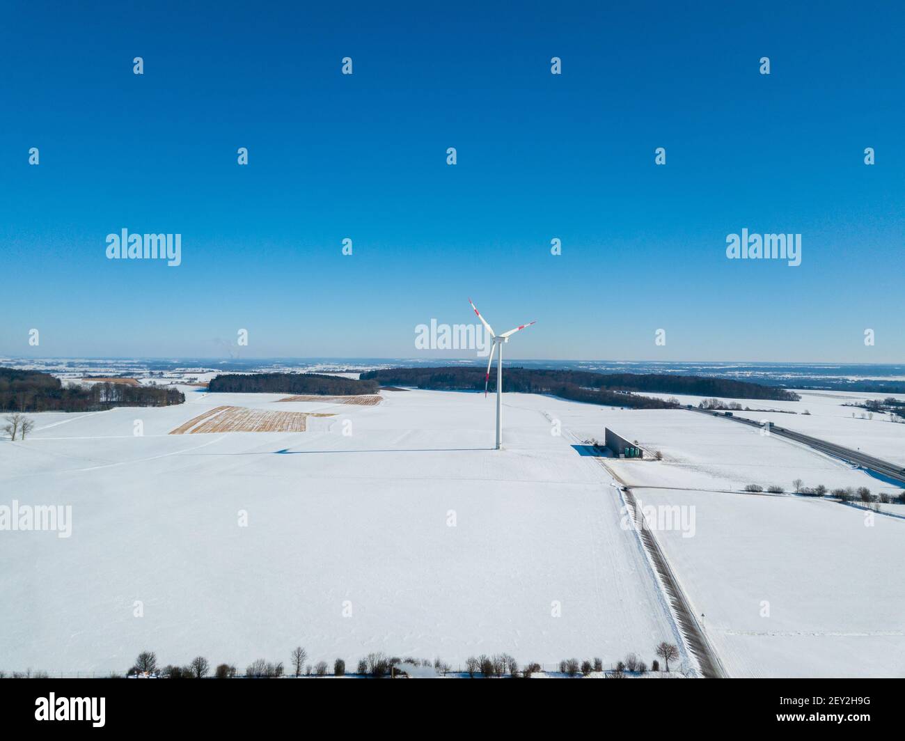 Aerial view of wind turbine in snow covered landscape next to highway ...