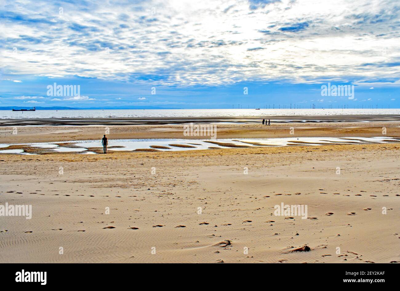 An art Statue in silhouette on the sandy Crosby beach, merseyside ...