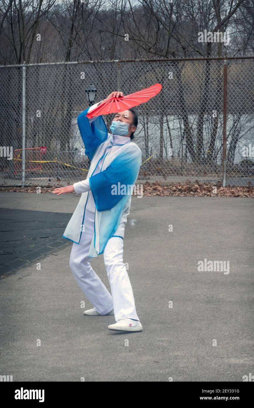 A middle aged Chinese American woman with a red fan, gracefully does ...