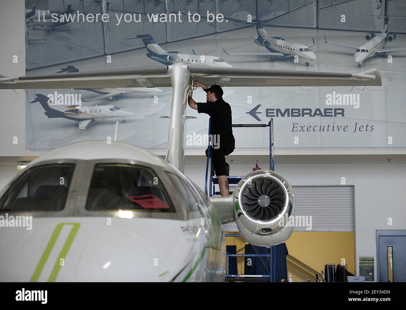 Shane Blume works at fine line taping on an Embraer Phenom 100 plane at ...