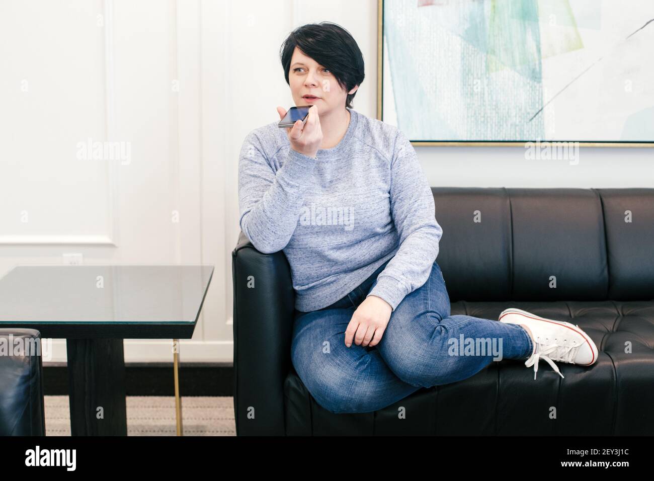 Middle age brunette woman sitting on couch sofa at home and talking on ...